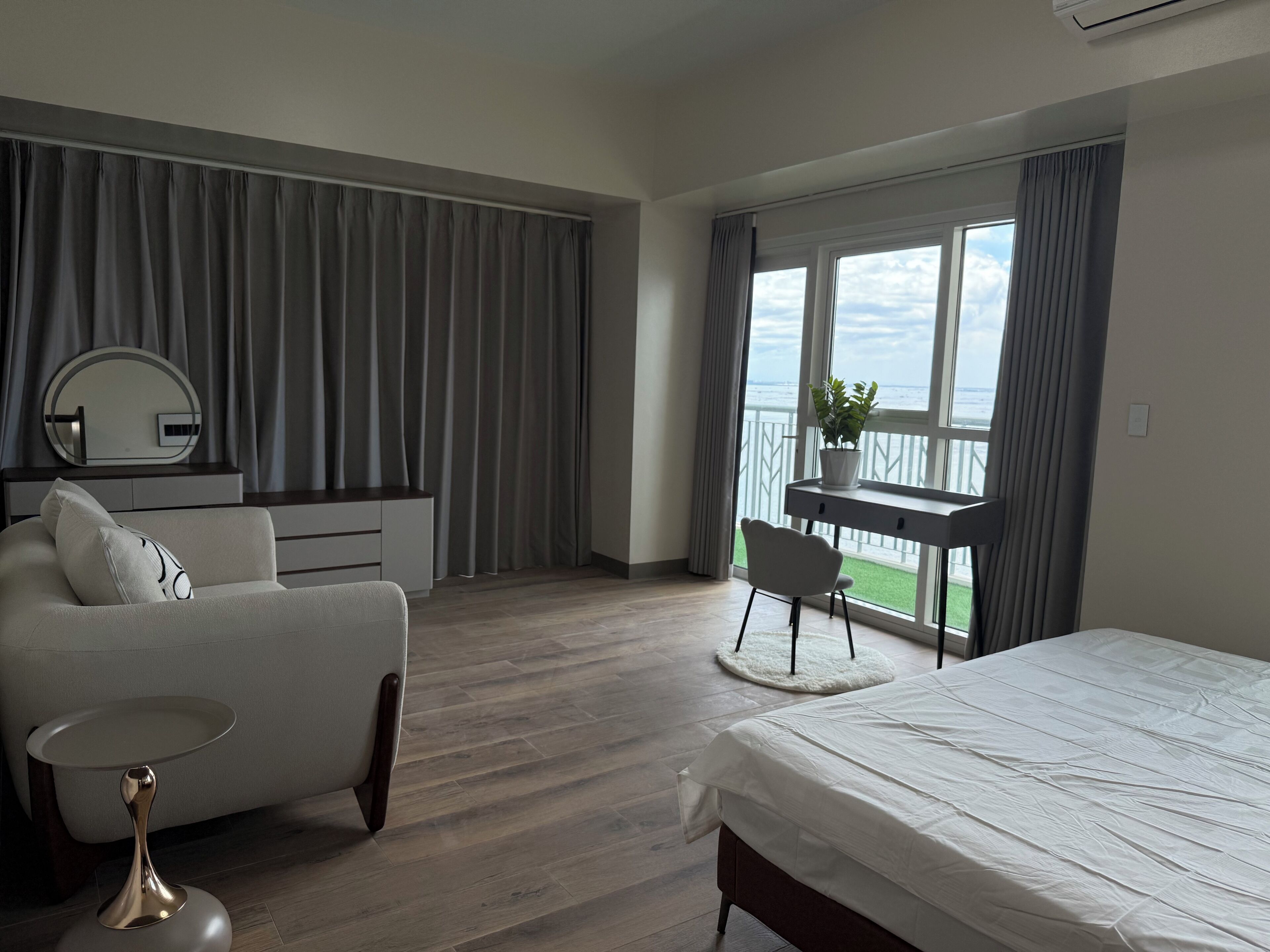 Quarto de hotel moderno com cama, sofá, escrivaninha e varanda com vista para o mar.