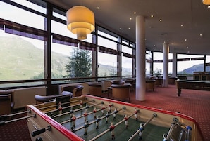 Um quarto espaçoso com mesa de futebol, assentos confortáveis e janelas amplas com vista para o exterior.