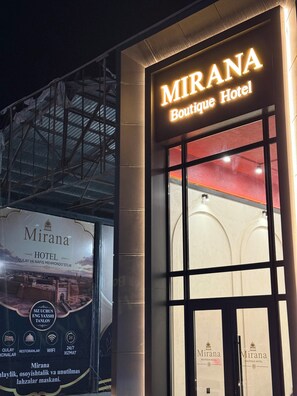 Exterior do Hotel Boutique Mirana com uma placa iluminada de destaque.