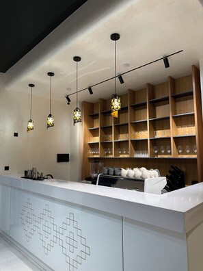 Uma cozinha moderna com luminárias pendentes, prateleiras de madeira e bancada branca.