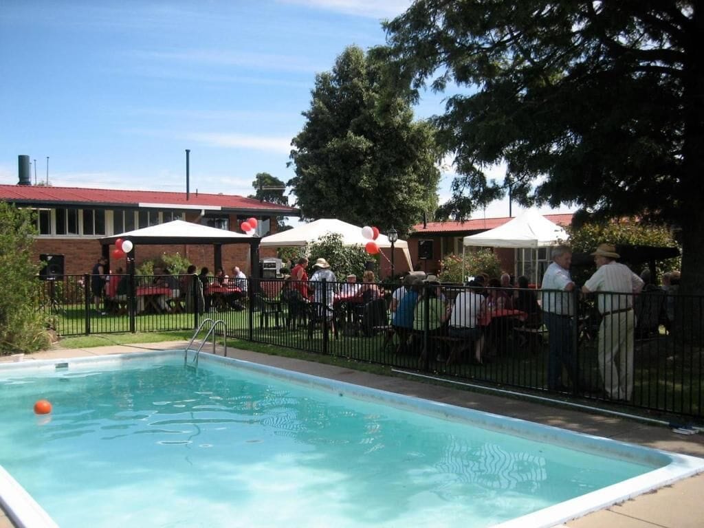 Piscina cercada por pessoas e guarda-sóis.