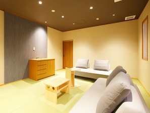 Quarto com sofá, armário de madeira e uma pequena mesa.