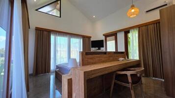 Quarto moderno com escrivaninha de madeira, uma cadeira, televisão e janelas amplas com cortinas.