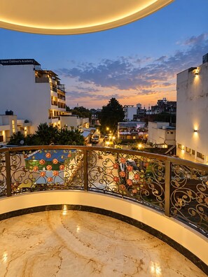 Uma varanda com vista para o horizonte urbano ao entardecer, com um edifício identificado como 'Grace Children's Academy'.