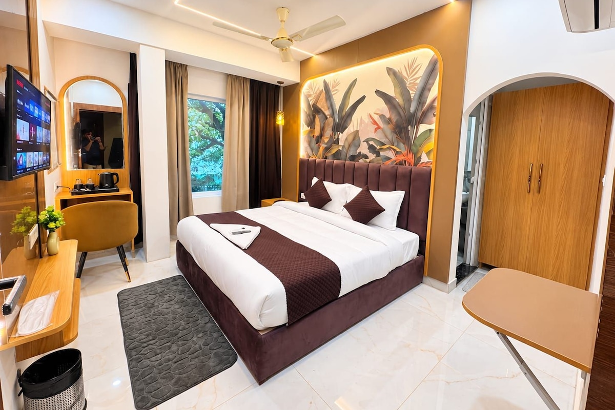 Quarto de hotel moderno com cama, escrivaninha, cadeira e televisão.