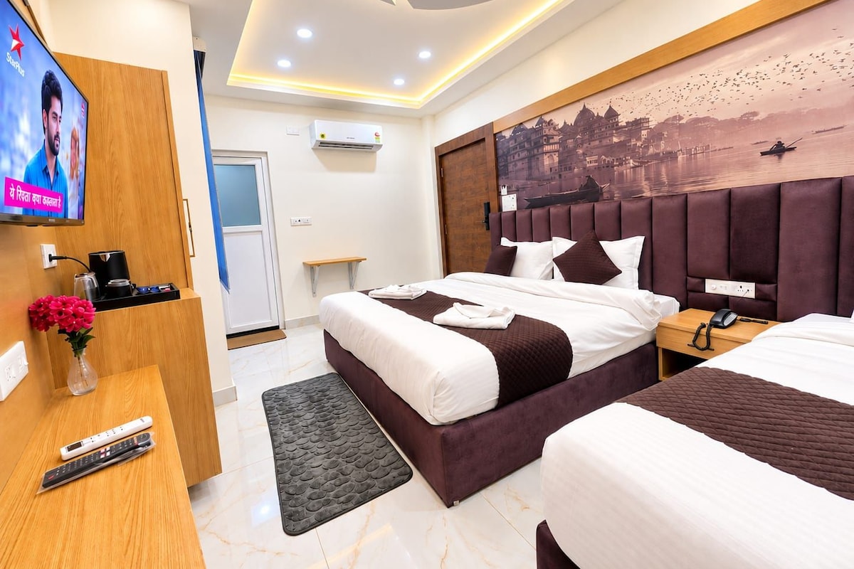 Quarto de hotel com cama, mesas de cabeceira, televisão e ar condicionado fixado na parede.