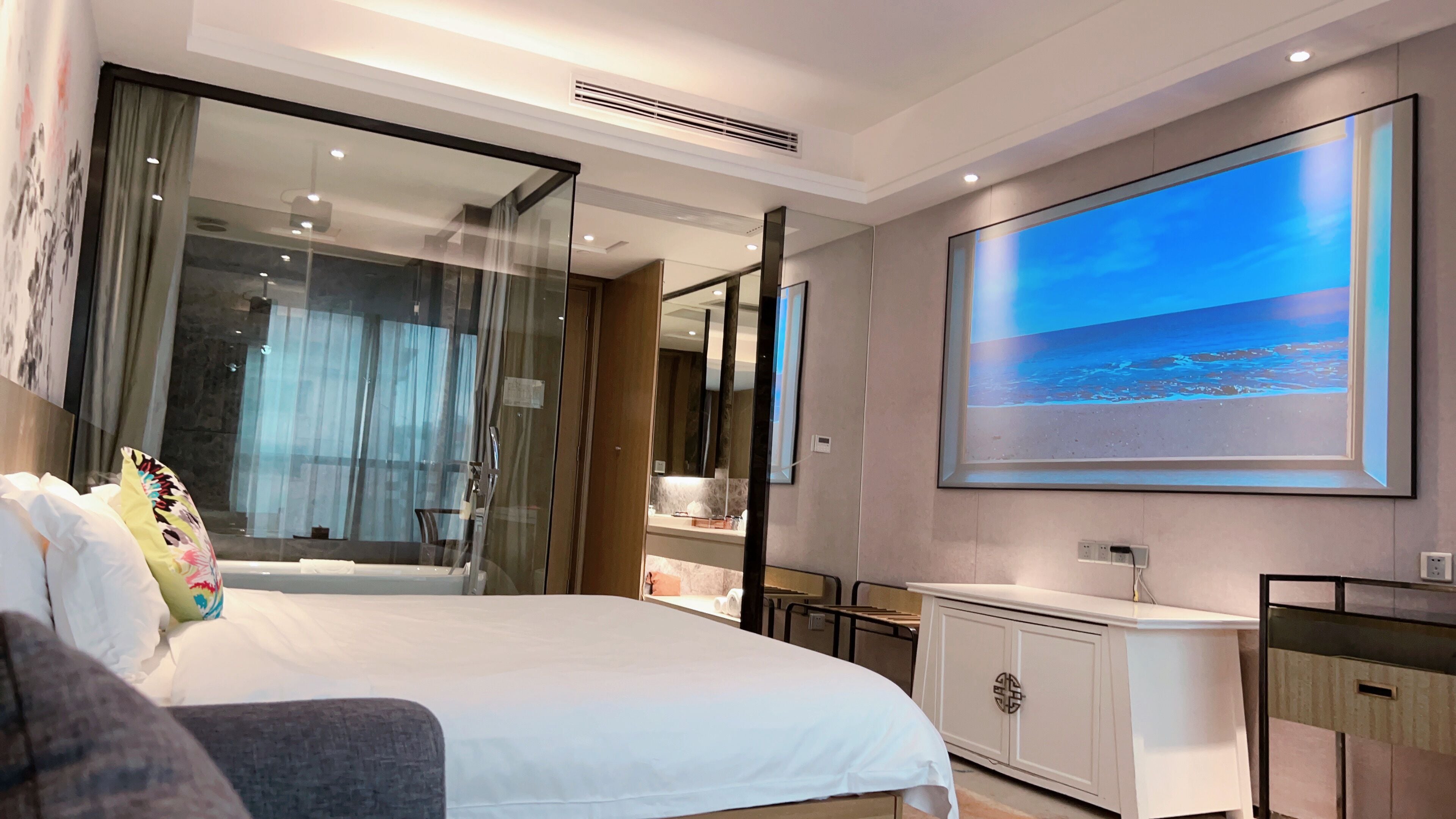 Quarto de hotel com cama, janela ampla e vista, guarda-roupa e espelho.