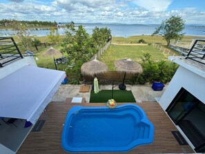 Piscina no terraço com vista para um lago e montanhas ao longe.