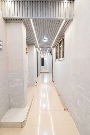 Um corredor com piso brilhante, paredes brancas e teto de metal.