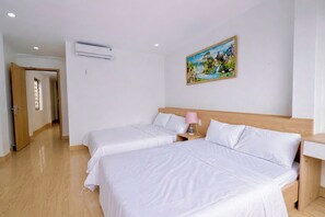Quarto de hotel com duas camas, cabeceira de madeira, um quadro na parede e um ar condicionado.