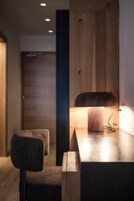 Um interior moderno com uma escrivaninha de madeira, uma cadeira e uma luminária na parede.