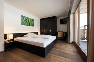 Quarto de hotel moderno com uma cama grande, televisão de tela plana, escrivaninha e vista para a varanda.