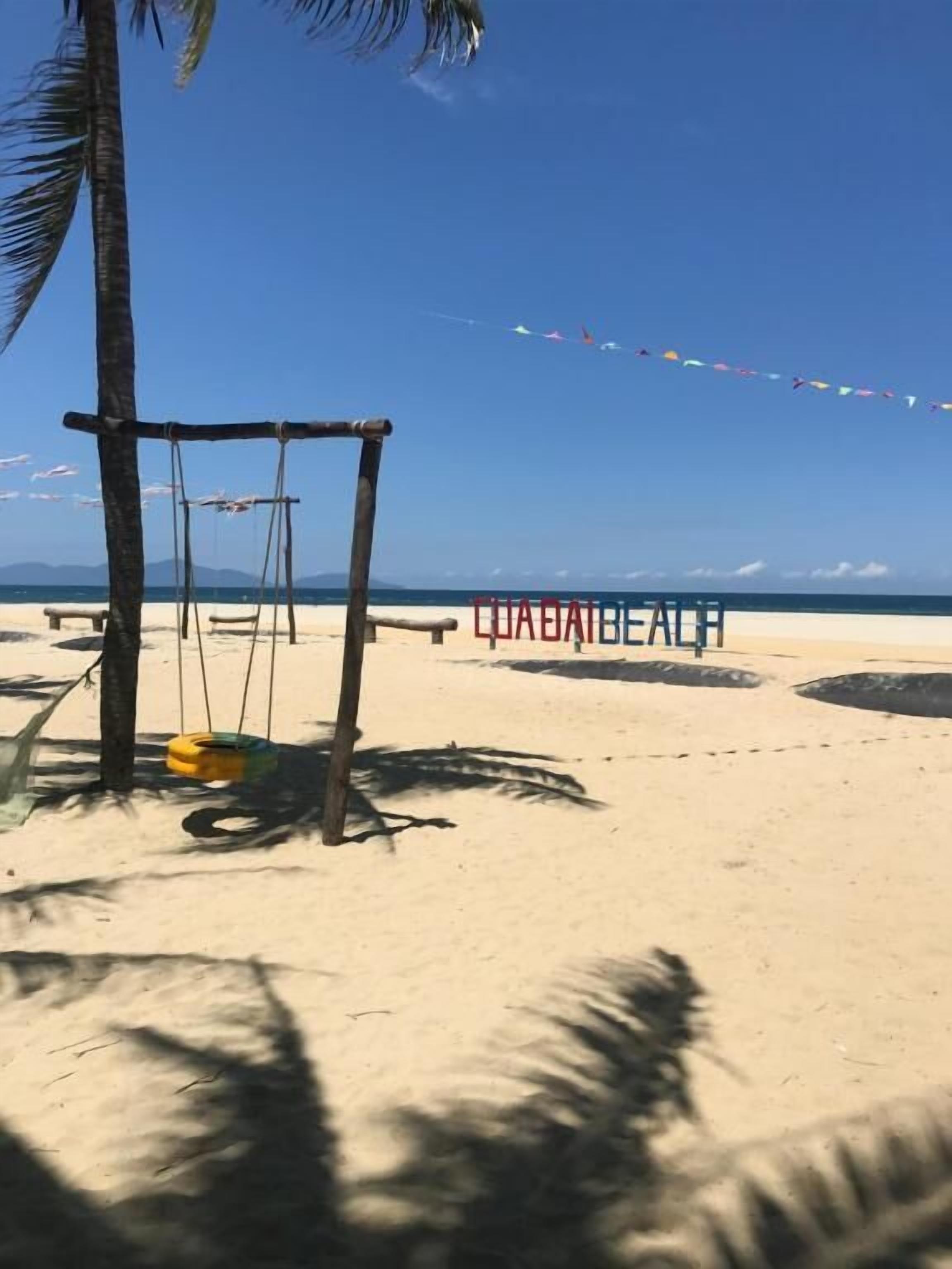 Uma praia com baloiço e placa com a inscrição 'LUMI BEACH'.