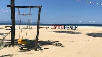 Uma praia com baloiço e placa com a inscrição 'LUMI BEACH'.