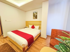 Quarto de hotel com cama, mesa de cabeceira e uma planta.