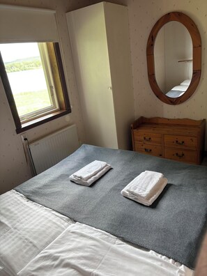 Quarto com cama, janela, penteadeira e espelho.