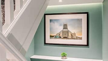Um quadro de uma igreja pendurado na parede, com um pequeno vaso de planta abaixo.