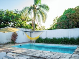 Piscina com rede, palmeiras e parede branca.