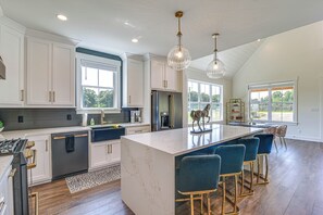 Uma cozinha moderna com uma ilha grande, banquetas e vista para o exterior.