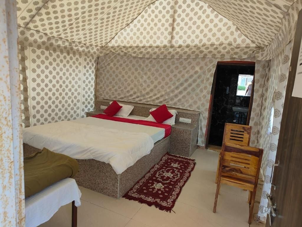 Um quarto com uma cama, uma cadeira e uma mesinha.