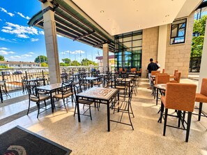 Um café ao ar livre com mesas e cadeiras, uma área coberta para sentar e vista para os arredores.