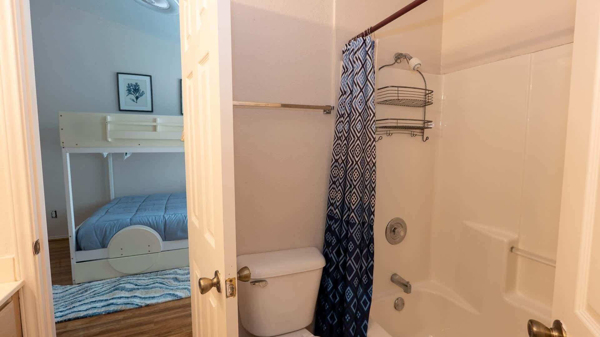 Quarto com beliche, sanitário e área de chuveiro.