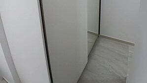 Um corredor estreito com uma porta branca e um espaço pequeno e sem detalhes no final.