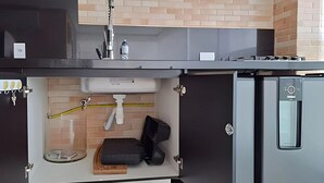 Uma cozinha com pia embutida, sistema de filtragem de água e geladeira compacta.