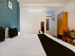 Quarto de hotel com uma cama, uma escrivaninha e um guarda-roupa.