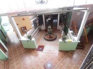 Um saguão com uma fonte central, balcão de recepção e escada.