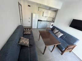 Um espaço compacto com um conjunto de sofá, uma mesa de jantar e uma TV fixada na parede.