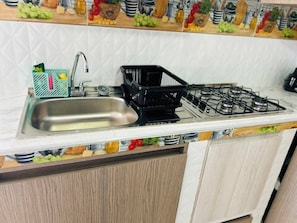 Uma cozinha com pia, fogão e diversos alimentos sobre o balcão.