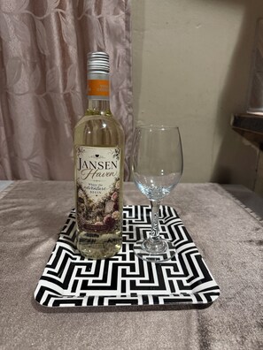 Uma garrafa de vinho Jansen Haven e um copo vazio sobre uma toalha de mesa estampada.