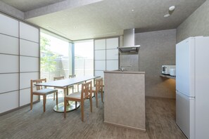 Uma cozinha moderna com área de refeições, apresentando uma ilha central, cadeiras de madeira e uma geladeira branca.
