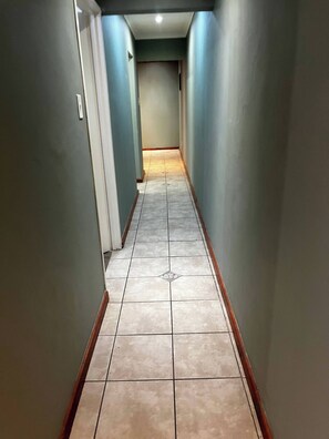 Um corredor estreito com paredes azul-claras e piso ladrilhado.