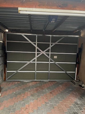 Uma garagem com porta de metal e chão de tijolos.