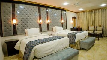 Quarto de hotel com duas camas, um espaço para sentar e um espelho grande.