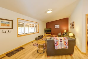 Uma sala de estar com sofá, mesa de centro, televisão e lareira.