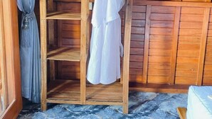 Uma prateleira de madeira com roupas penduradas e um par de sapatos.
