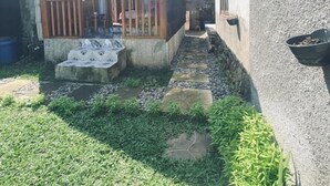 Uma cabana de madeira com varanda, um caminho de pedra e um pequeno jardim.