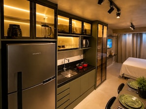 Cozinha compacta com geladeira, micro-ondas e pia.