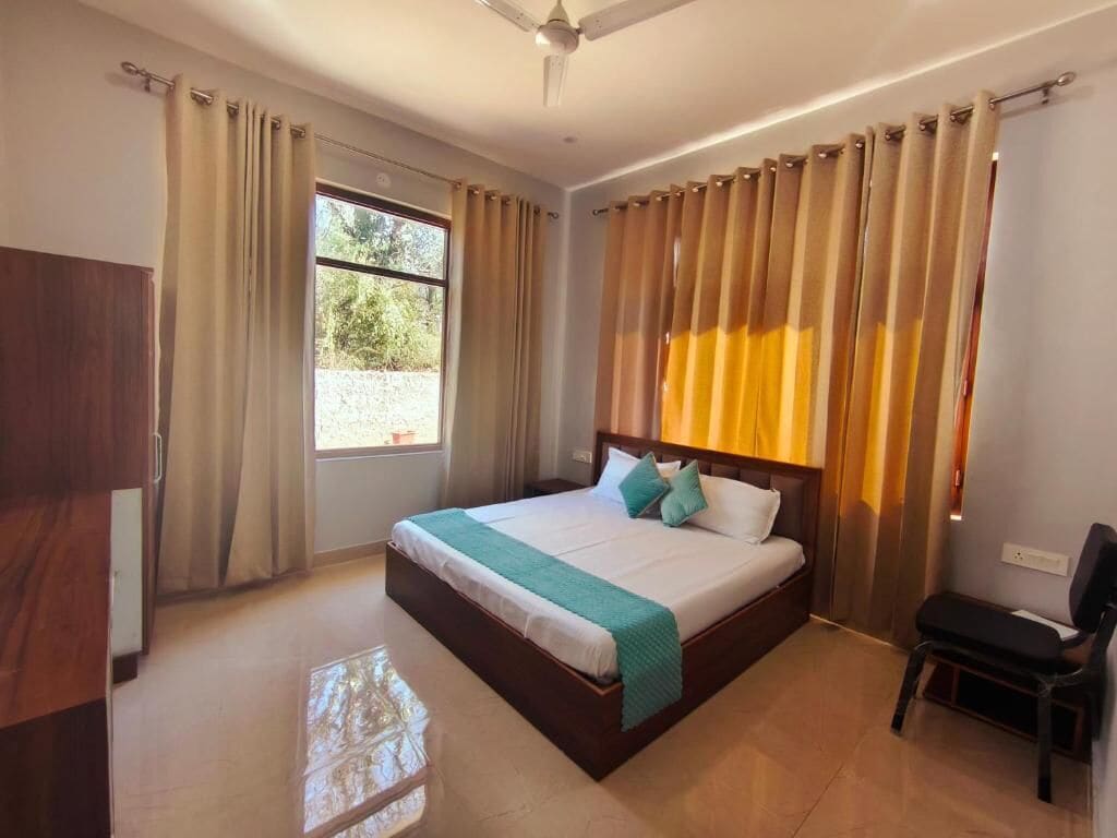 Quarto com cama, cadeira, escrivaninha e janela.