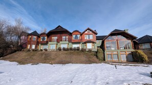 Uma casa de madeira grande, com vários andares, fachada verde e várias janelas.