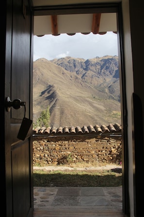 Uma porta que dá para uma varanda com vista para uma paisagem montanhosa.