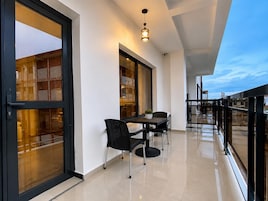 Varanda moderna com porta de vidro, mesa de jantar com cadeiras e luminária pendente.