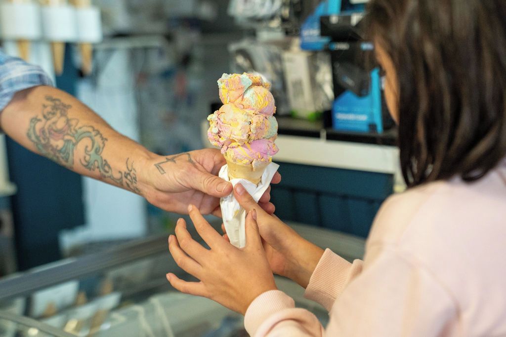 Uma pessoa segurando um cone de sorvete colorido.