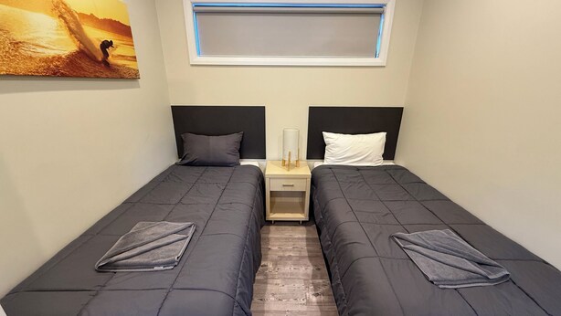 Quarto com duas camas, mesa de cabeceira, janela e um quadro na parede.
