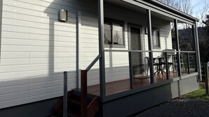 Uma casa moderna com varanda coberta, escadaria e vista para a paisagem ao redor.