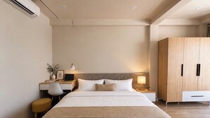 Quarto de hotel com cama, mesa de cabeceira, luminária e armário.