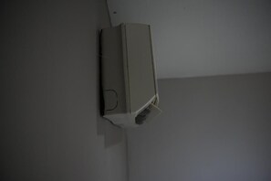 Um objeto branco e retangular fixado na parede, possivelmente um termostato ou painel de controle.
